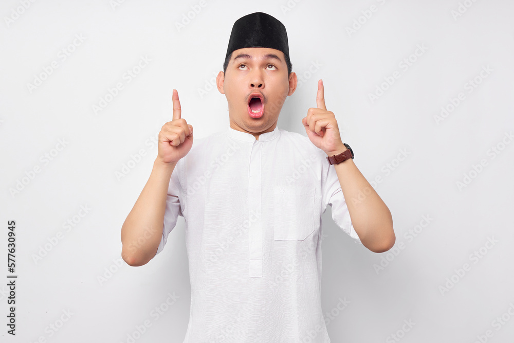 Shocked handsome young Asian Muslim man wearing Arabic costume pointing ...