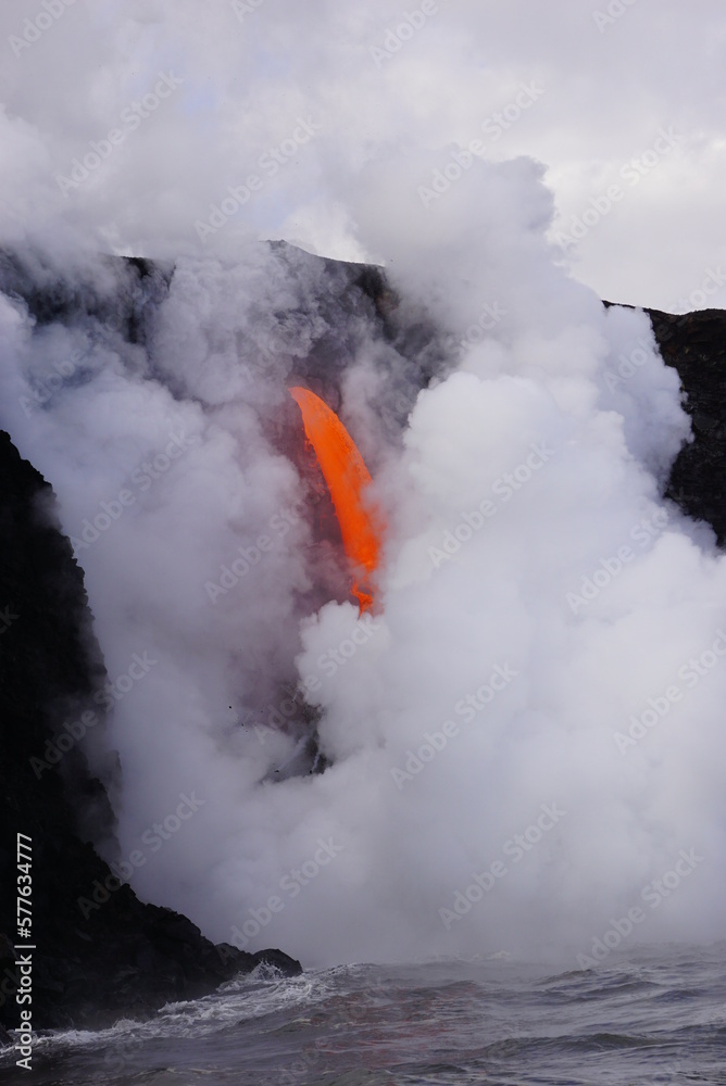 Hot lava stream flowing down from high cliff into the ocean surrouded ...