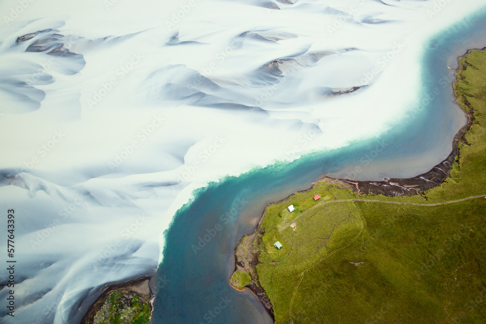 Houses give scale to a fresh water stream and a glacial silt river ...