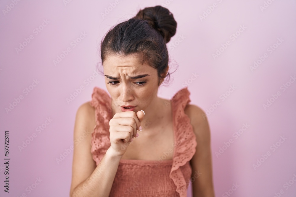 Young teenager girl standing over pink background feeling unwell and ...
