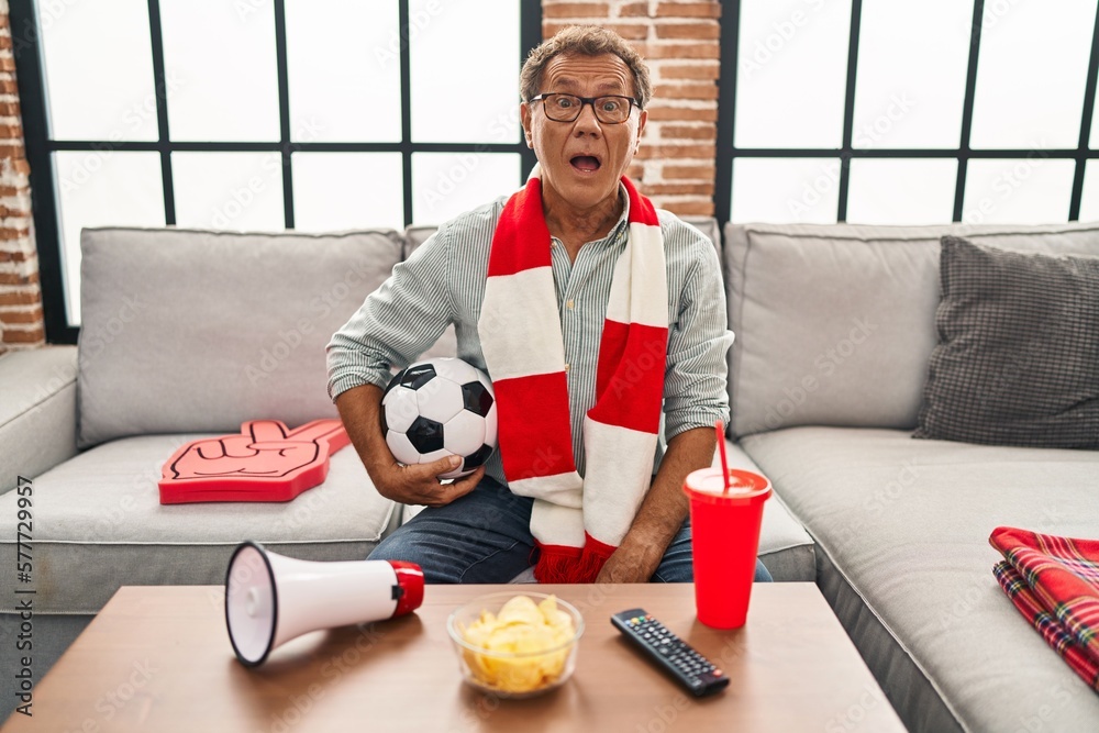 Senior man watching football holding ball supporting team scared and ...