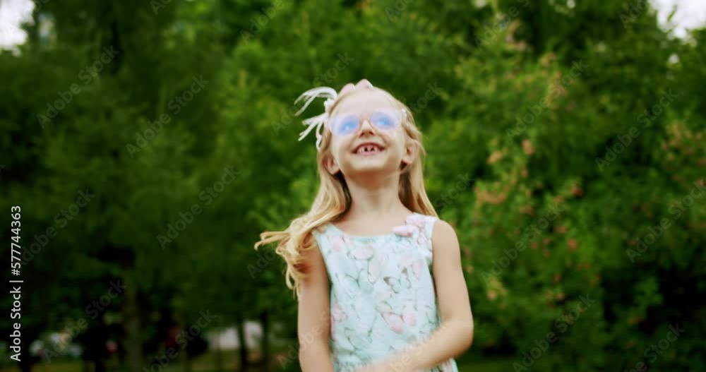 Laughing girl catching soap bubbles in park. Amazed preteen girl in ...