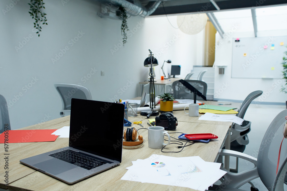 Office in use without people. Office desk cluttered with laptop and ...