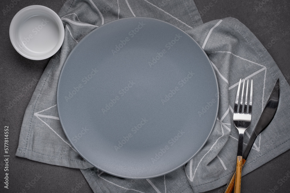 Empty gray matte plate and gray napkin on gray stone tabletop. Copy ...
