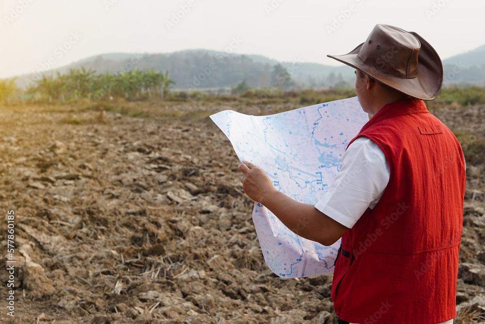 Foto de Asian man explorer wears hat, red vest shirt, holds map to ...