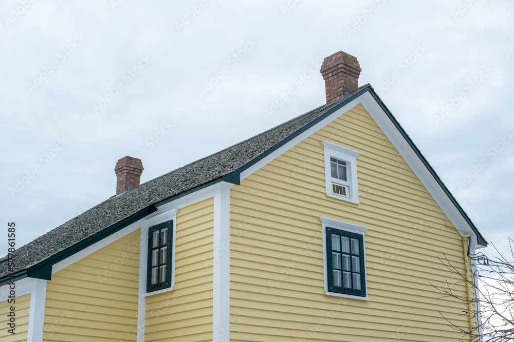 A large yellow wooden vintage building with lots of windows, dormers ...