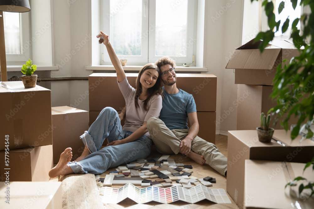 Happy young married couple enjoying moving into new flat, sitting on ...