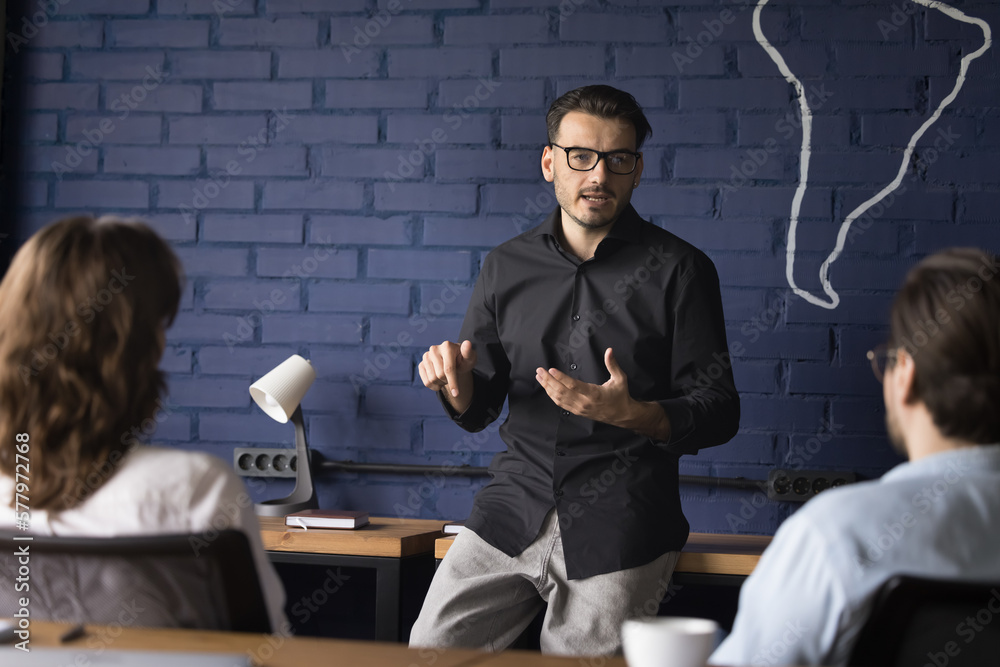 Serious confident smart business group leader instructing team, telling ...
