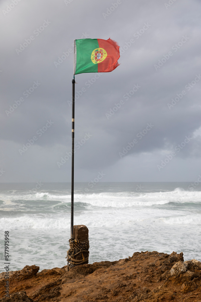 Portuguese flag flying in wind with stormy Atlantic Ocean waves ...