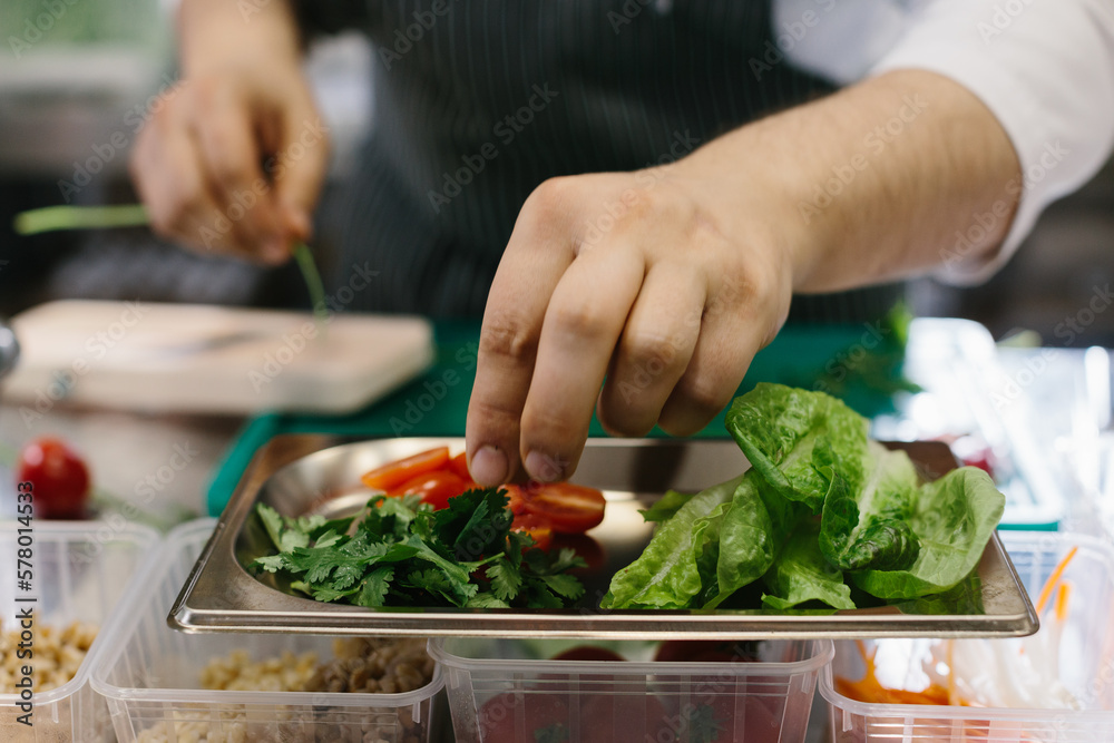 Preparing vegetables for a delicious bowl dish: a male chef in a ...