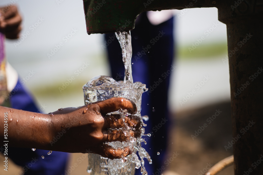Closeup of a child hand collecting fresh drinking water from local tube ...