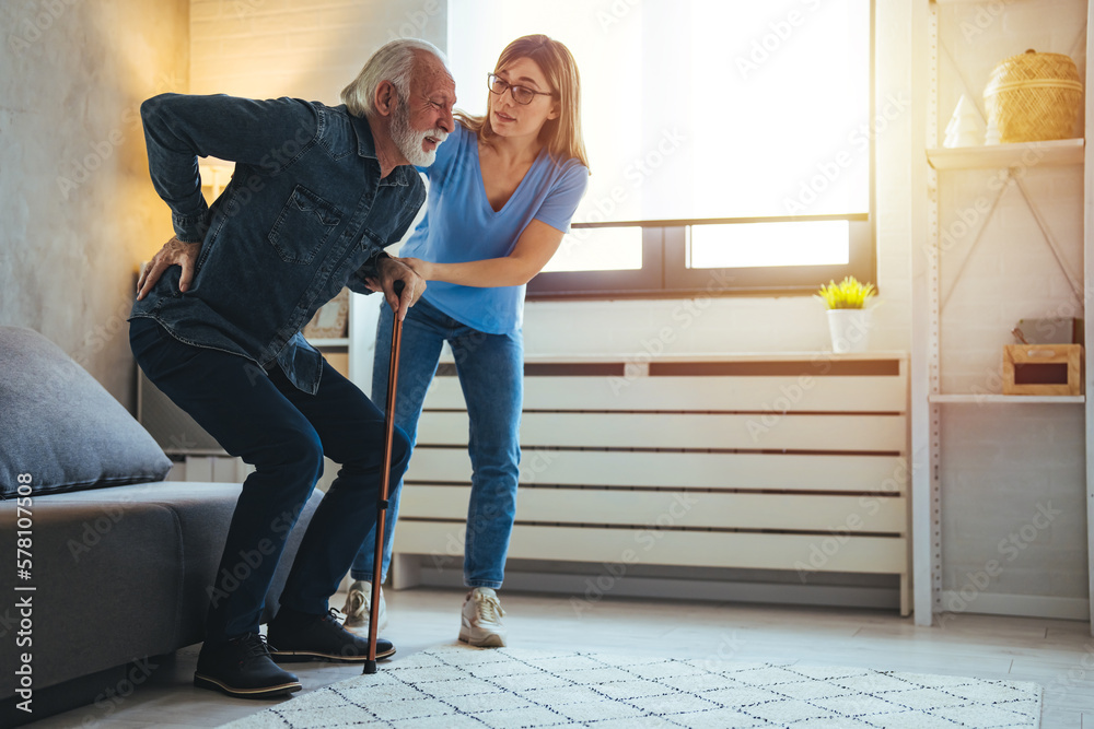 Smiling nurse assisting senior man to get up from bed. Caring nurse supporting patient while ...