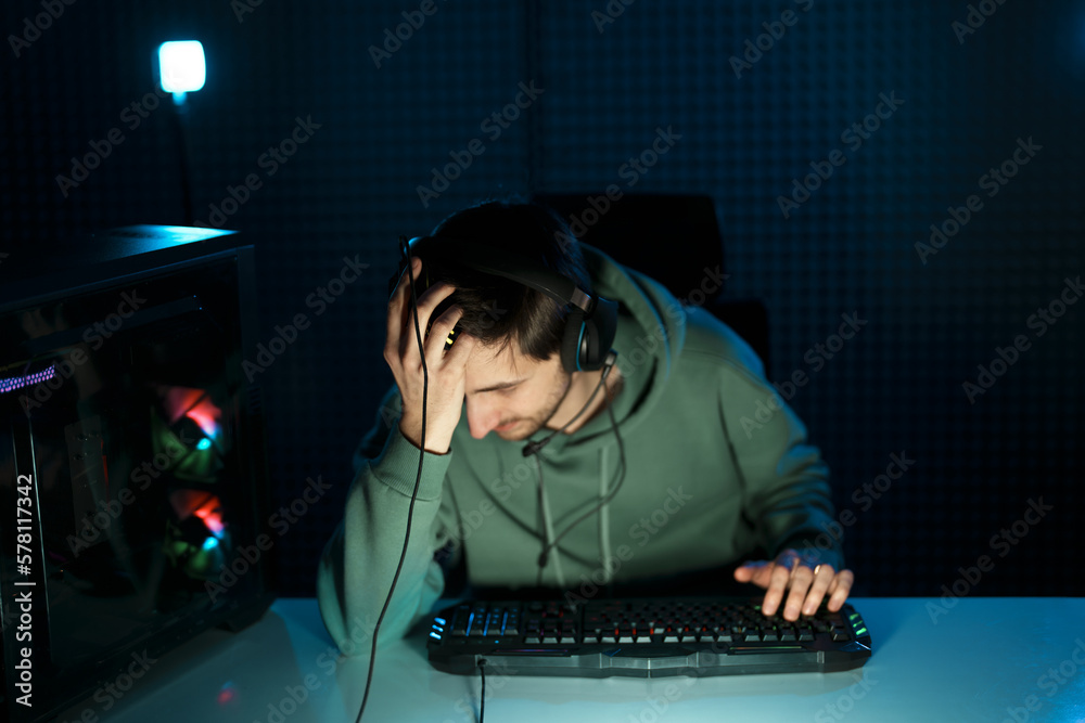 Young male cybersport gamer in headset with microphone using keyboard ...