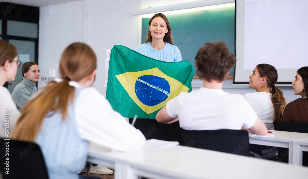 Adult female teacher in the classroom showing the flag of Brazil to the ...