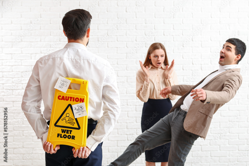 Young man with caution sign playing a prank on his colleagues against ...