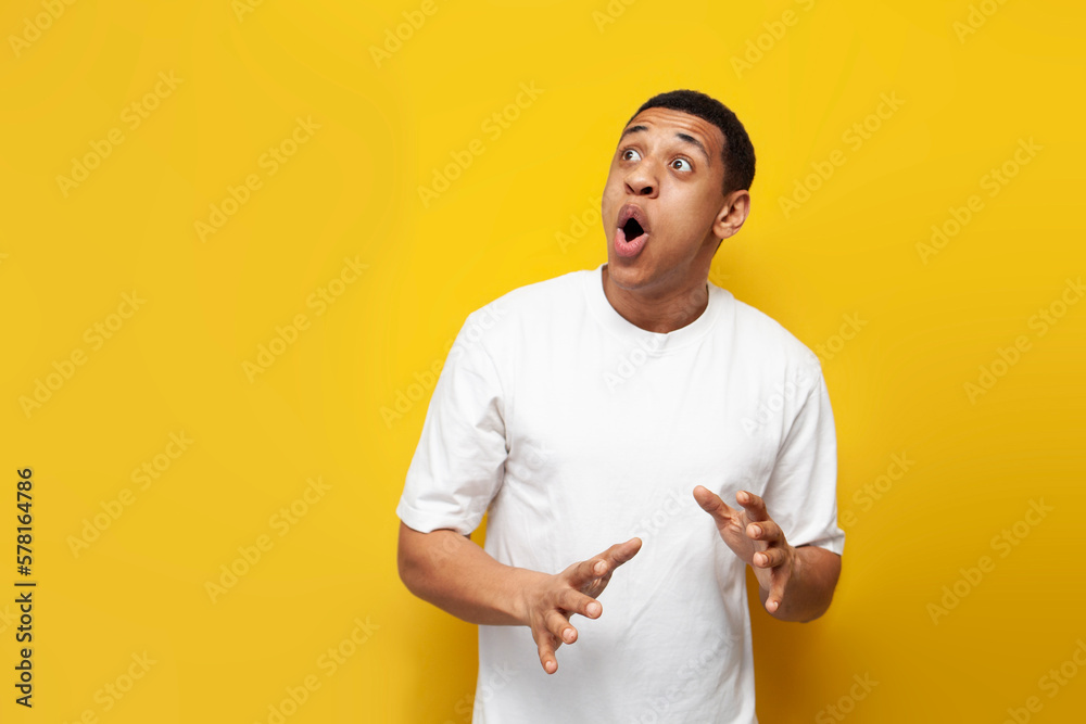 young shocked african american guy in white oversized t-shirt is ...
