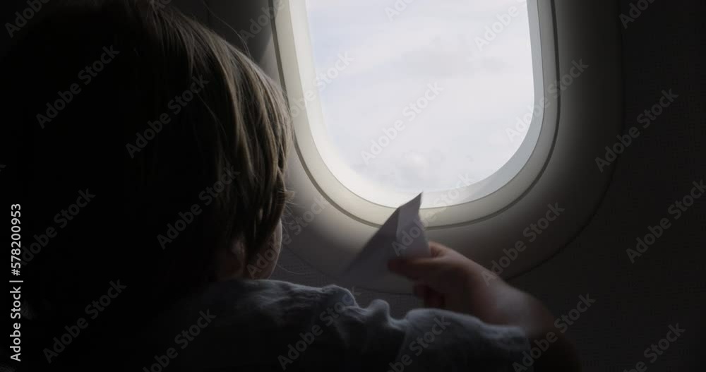 Vidéo Stock Little cute child is playing with paper plane while sitting ...