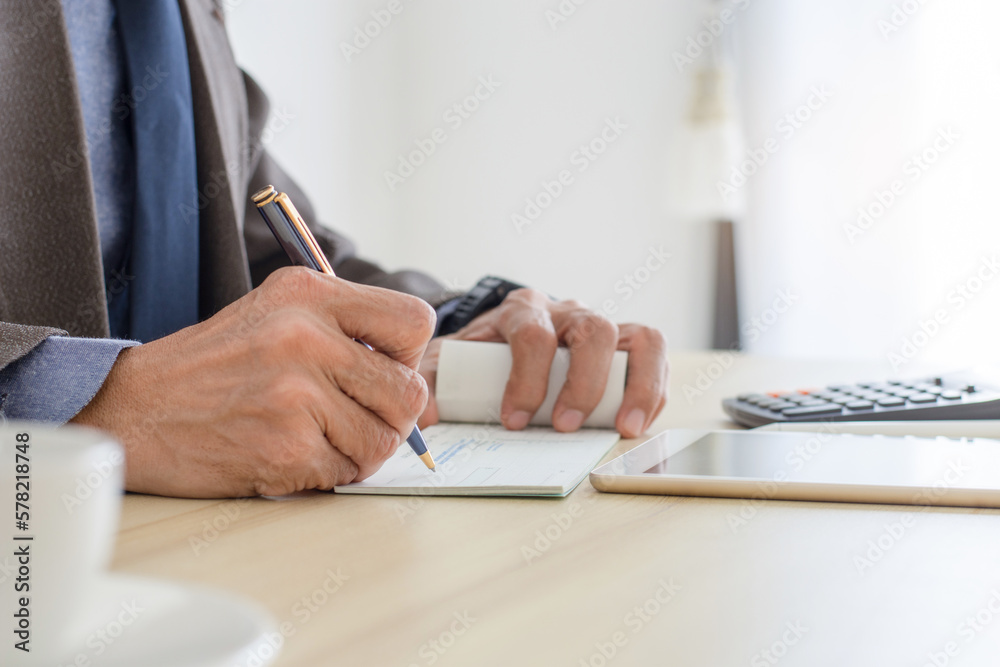 Businessman hand write and sign cheque book with digital tablet r on ...