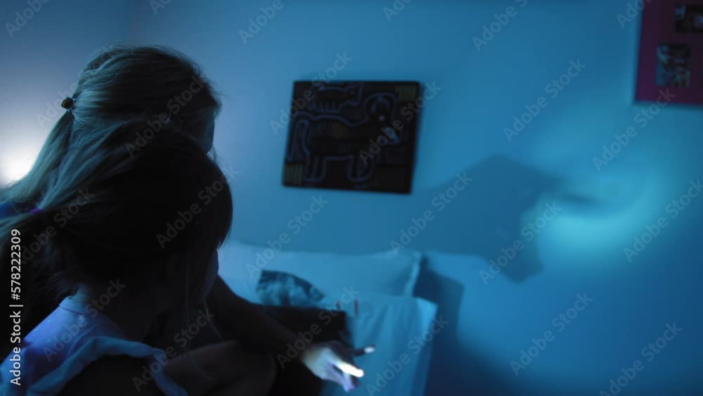 Mom making shadow puppets on a wall to tell daughter a bedtime story ...