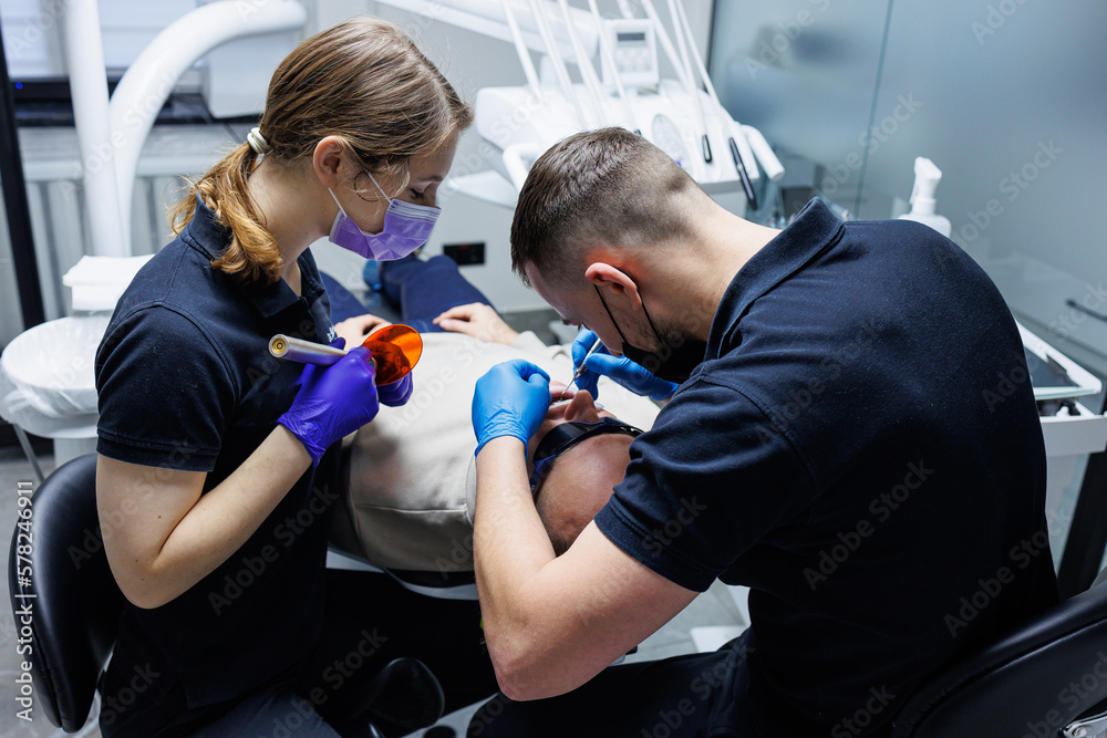 An orthodontist with an assistant treats teeth using dental instruments ...