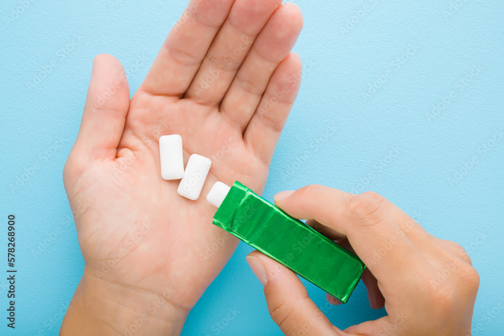 Young adult woman hand pouring white chewing gum pads from green pack ...