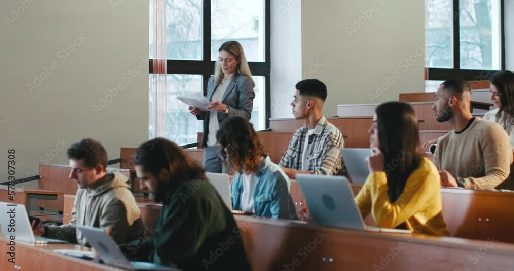 Female professor of University handing out tasks for exam to mixed ...