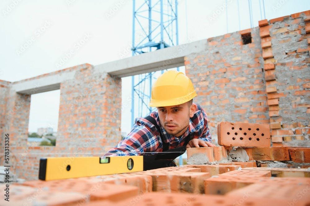 Installing brick wall. Construction worker in uniform and safety ...