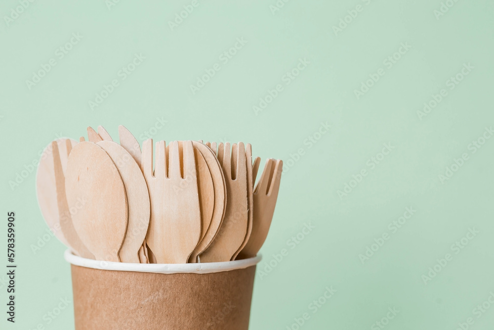 Eco-friendly disposable kitchen utensils in a paper cup on a beige ...