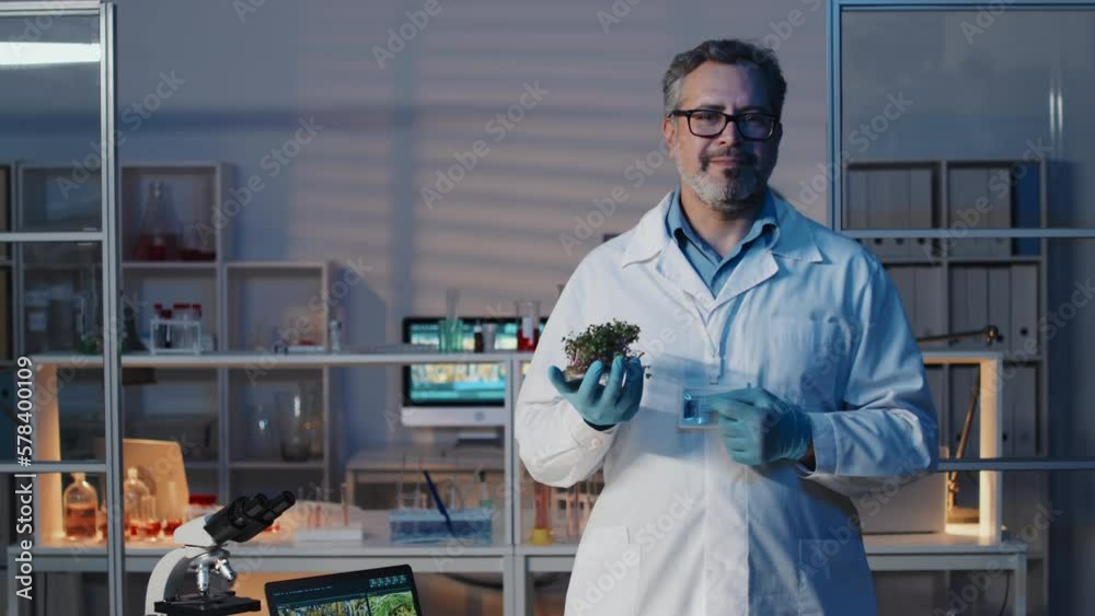 Successful mature microbiologist in lab coat, gloves and eyeglasses ...