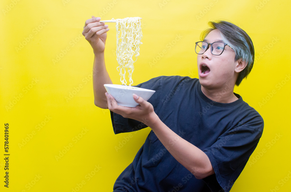 Happy attractive asian man with peek a boo hair eats noodles on bowl ...