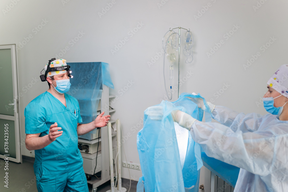 Nurse ties a sterile gown to the surgeon before the operation. Doctors ...
