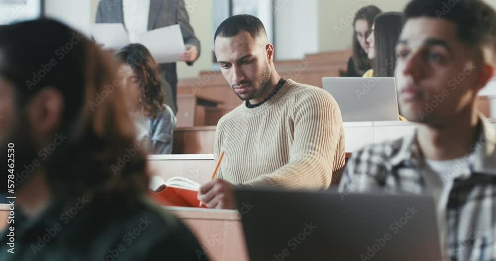 Handsome young African American male student writing down test and ...