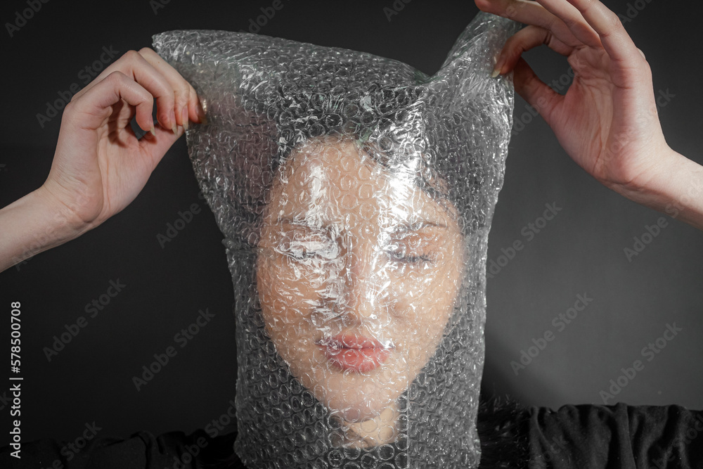 Portrait of a poor skinny girl in black crumpled clothes with a plastic ...