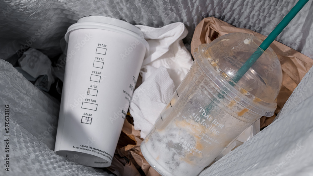 Starbucks coffee cup and caramel frappuccino cup inside a trash can ...