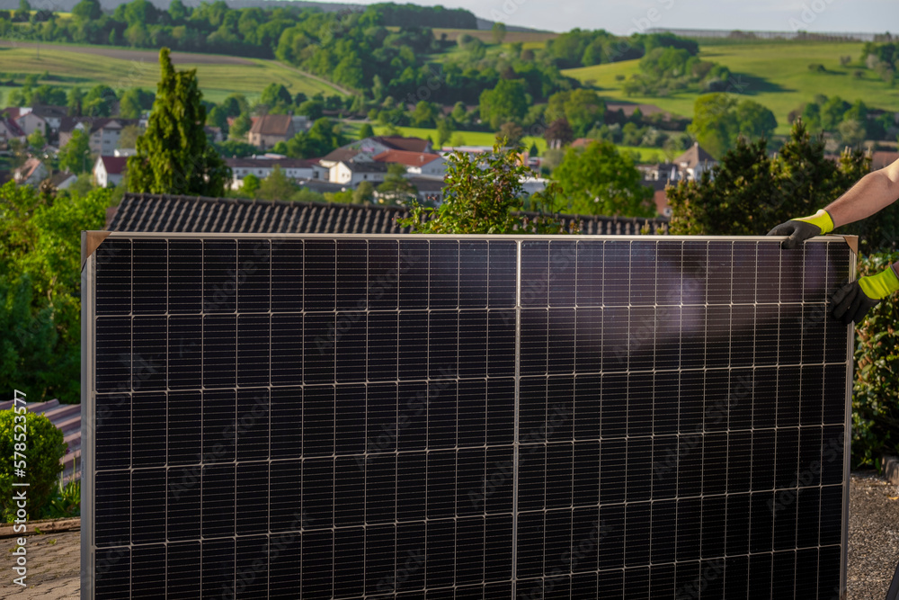 Solar panel in the hands on city houses background.Fitting and ...