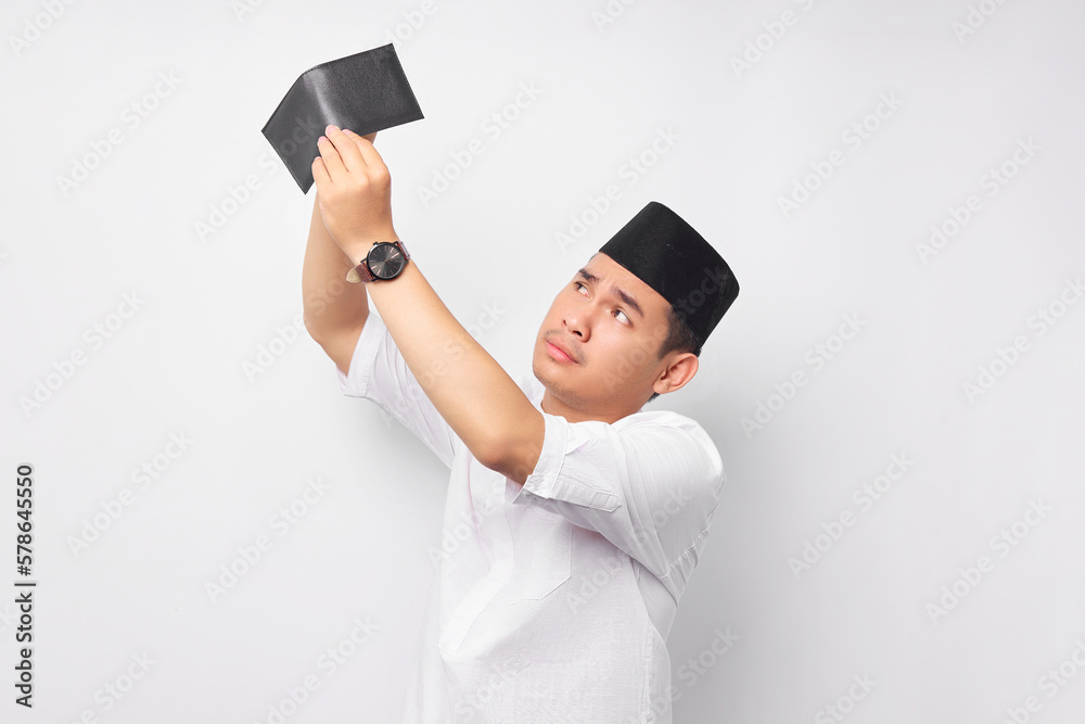 Sad young Asian Muslim man in Arabic clothes looking empty wallet ...