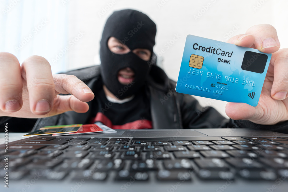 Man in robber mask uses internet, bank account and credit facilities. Phishing attack by male ...