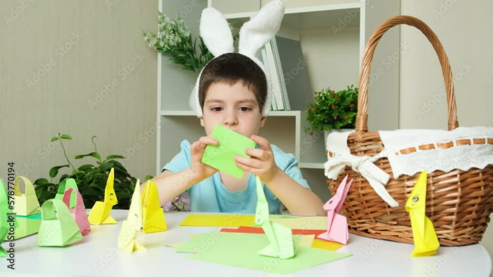 Preschool boy with rabbit ears nag head makes Easter crafts, origami ...