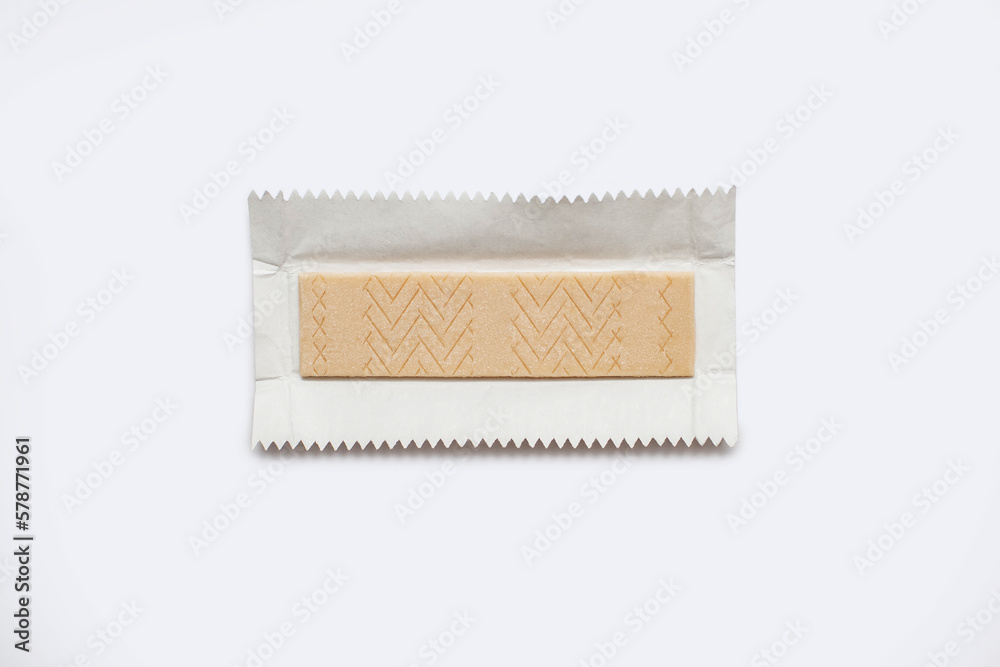 A piece of chewing gum in an unpacked wrapper on a white background ...