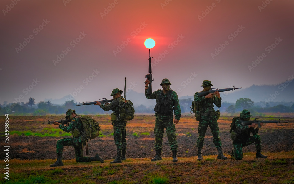 Five soldiers are standing and aiming their weapons on the battlefield ...