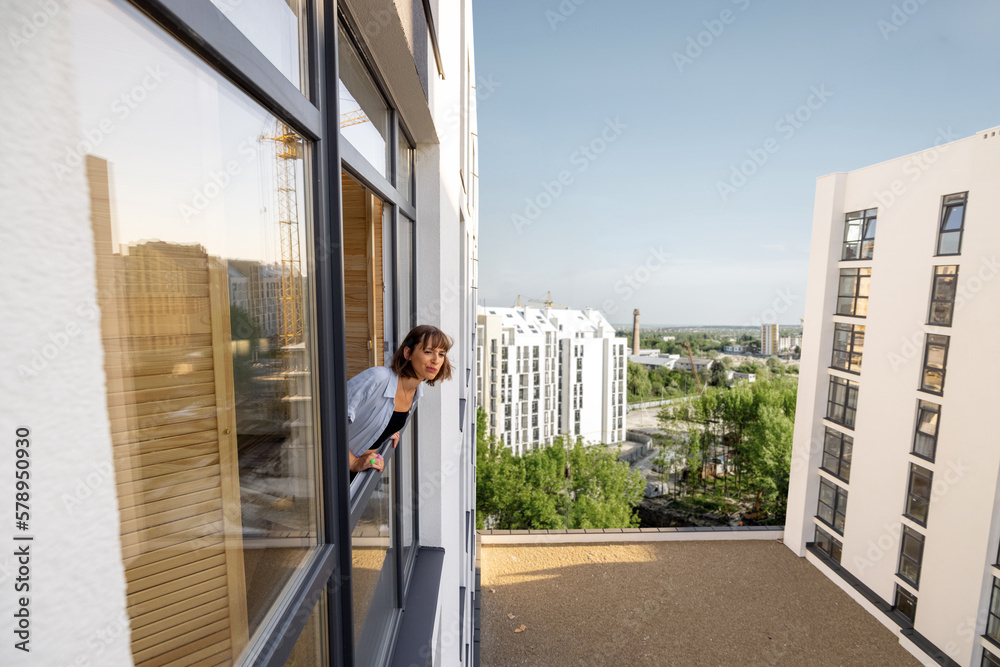 Angry woman looks out the window of residential building in city, urban ...