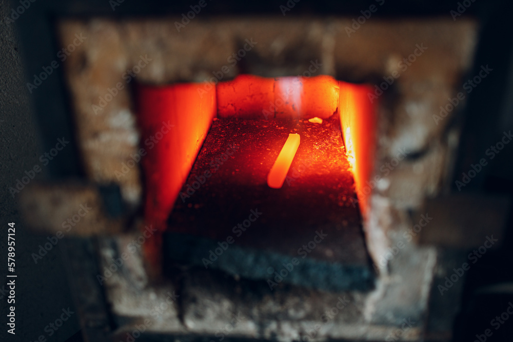 Blacksmith forge oven with hot flame. Smith heating iron piece of steel ...
