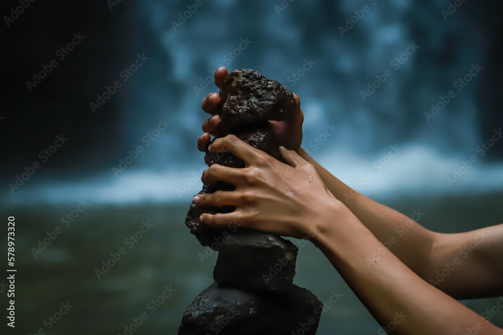 Someone is making Stone tower with hand on the waterfall and blur ...