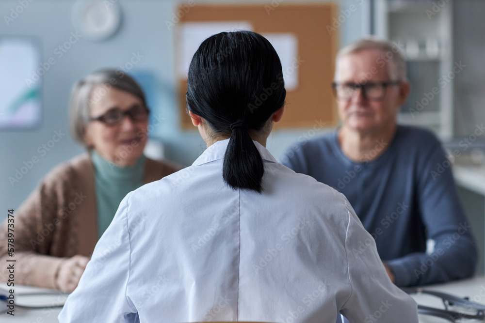 Back view of female doctor working with senior couple in medical clinic ...