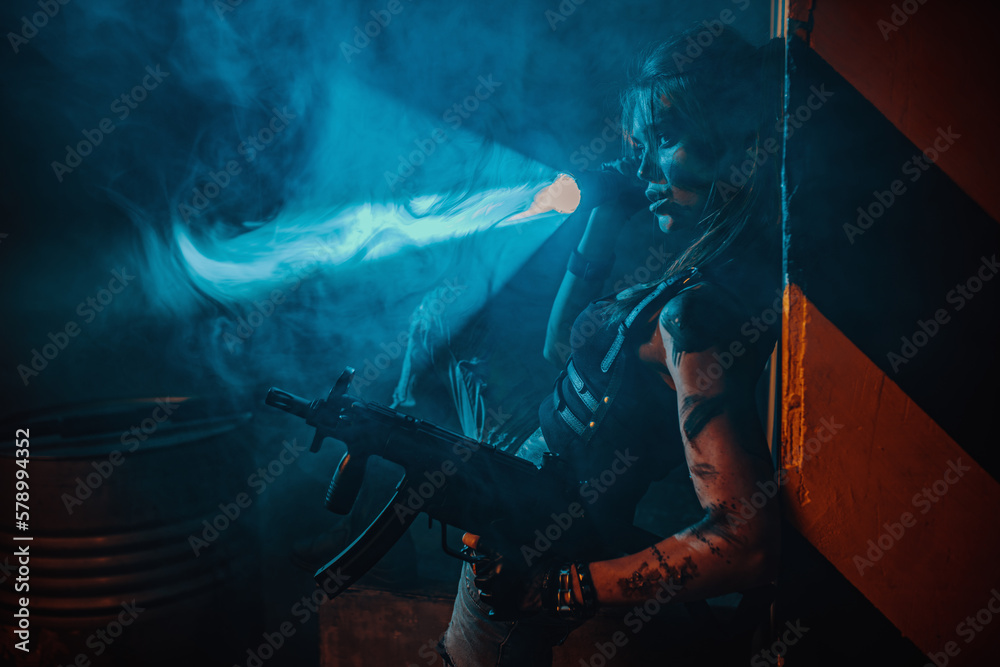 Young woman fighter with gun and flashlight in dramatic industrial ...