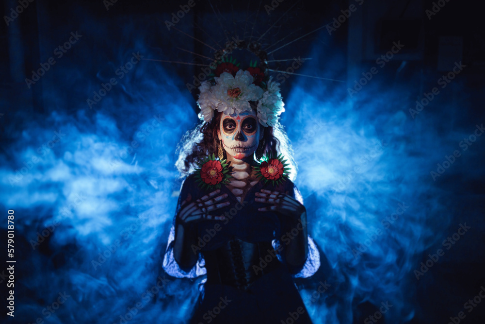 Woman with mexican skull halloween makeup in dark with backlight rays ...