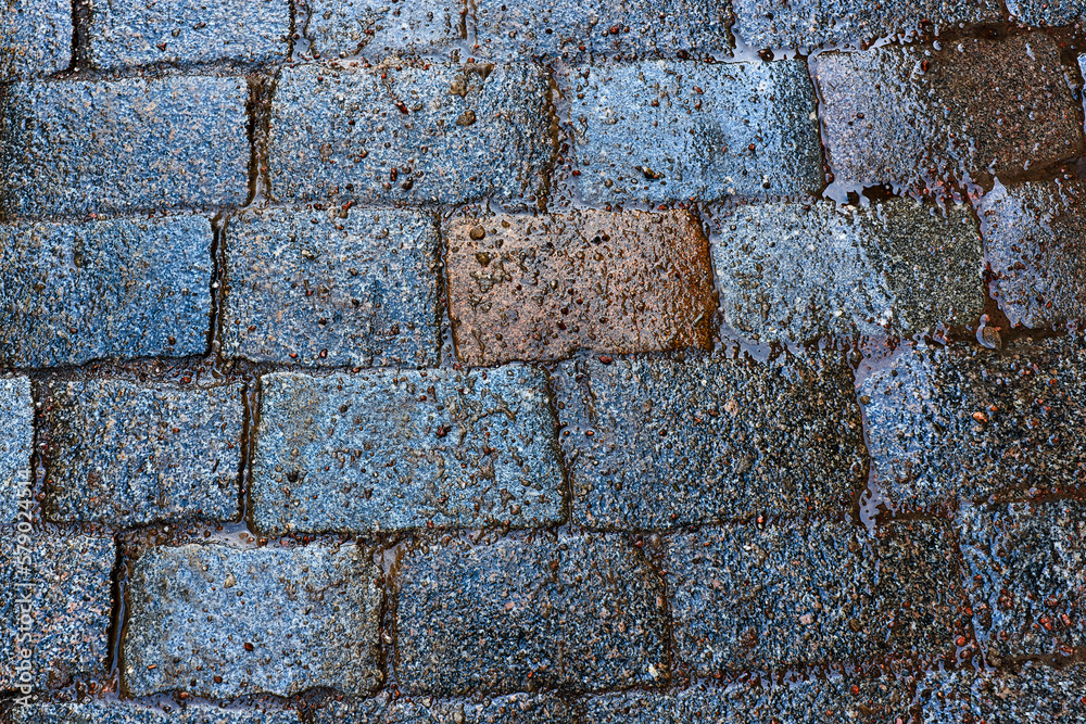 Foto de Hard paved road surface of hewn stone. Wet stone pavement with ...