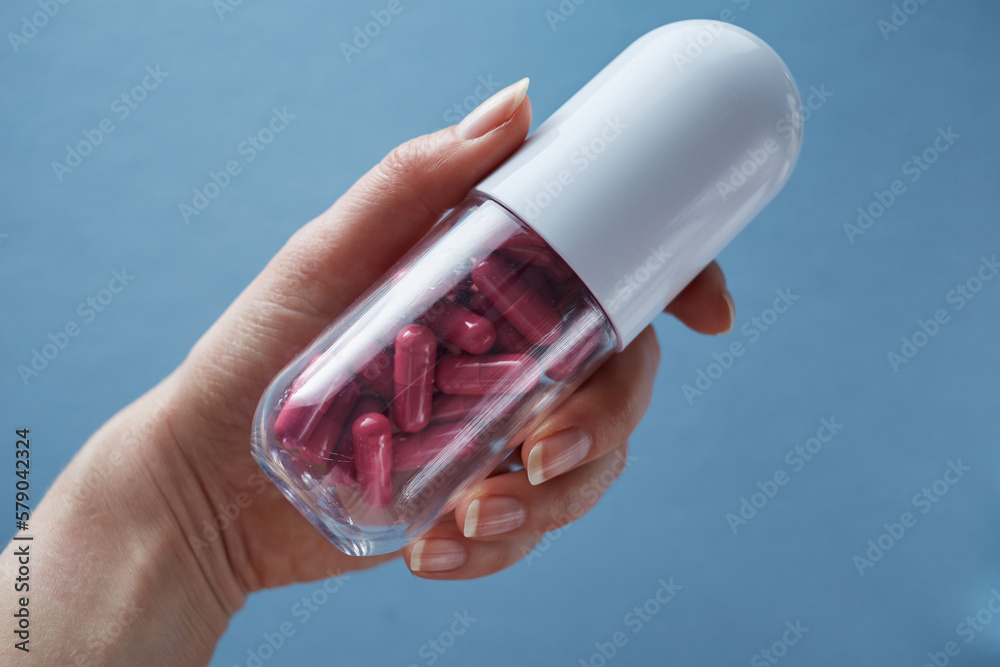 Giant capsule container filled with pink capsules in hand Stock Photo ...