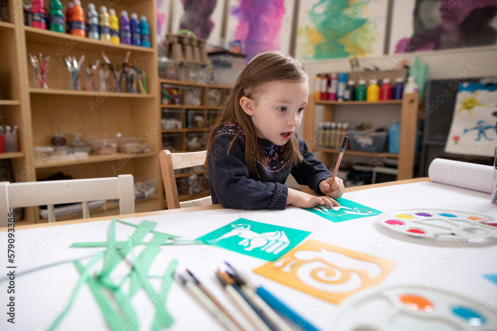 Preschool girl with stencils making art and craft project in classroom ...