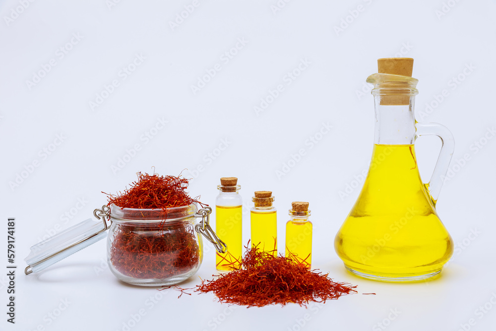 Dried saffron threads in glass bottle and oil extract on white ...